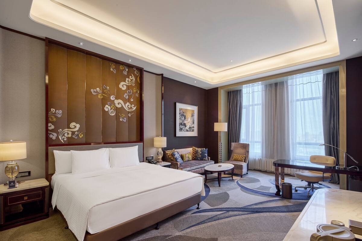 Quarto de hotel com uma cama grande, um sofá, uma escrivaninha e uma cadeira.