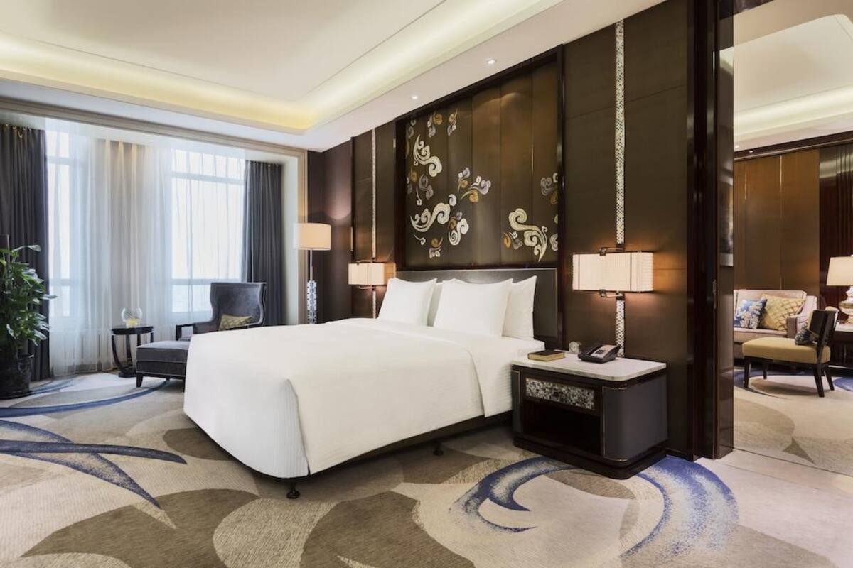 Quarto de hotel com uma cama grande, mesas de cabeceira, uma escrivaninha e uma cadeira.