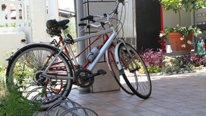 Uma bicicleta estacionada ao lado de um edifício com chão de azulejos e plantas em vasos.