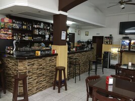 Uma área de bar com balcão, banquetas e frigorífico.