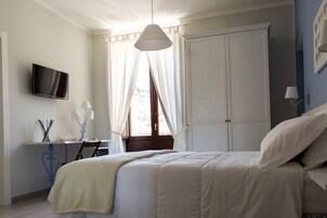 Quarto com cama, escrivaninha, televisão e guarda-roupa.