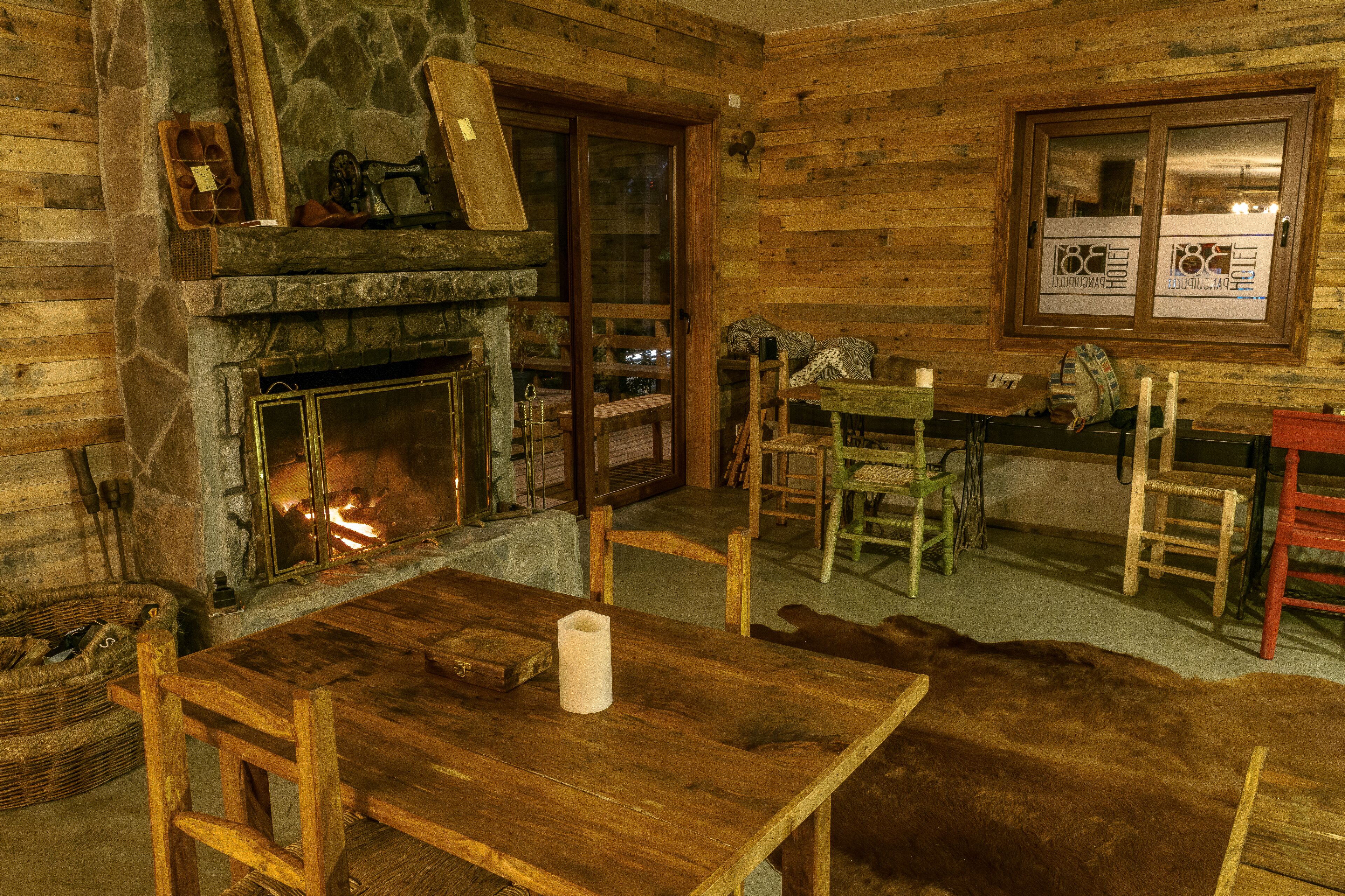 Interior rústico de cabana com lareira de pedra, móveis de madeira e tapete de pele.