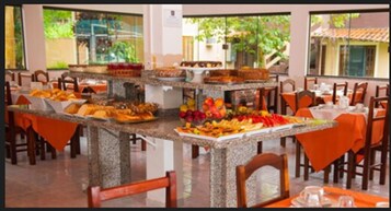 Disposição de buffet com diversos alimentos e vista tropical.
