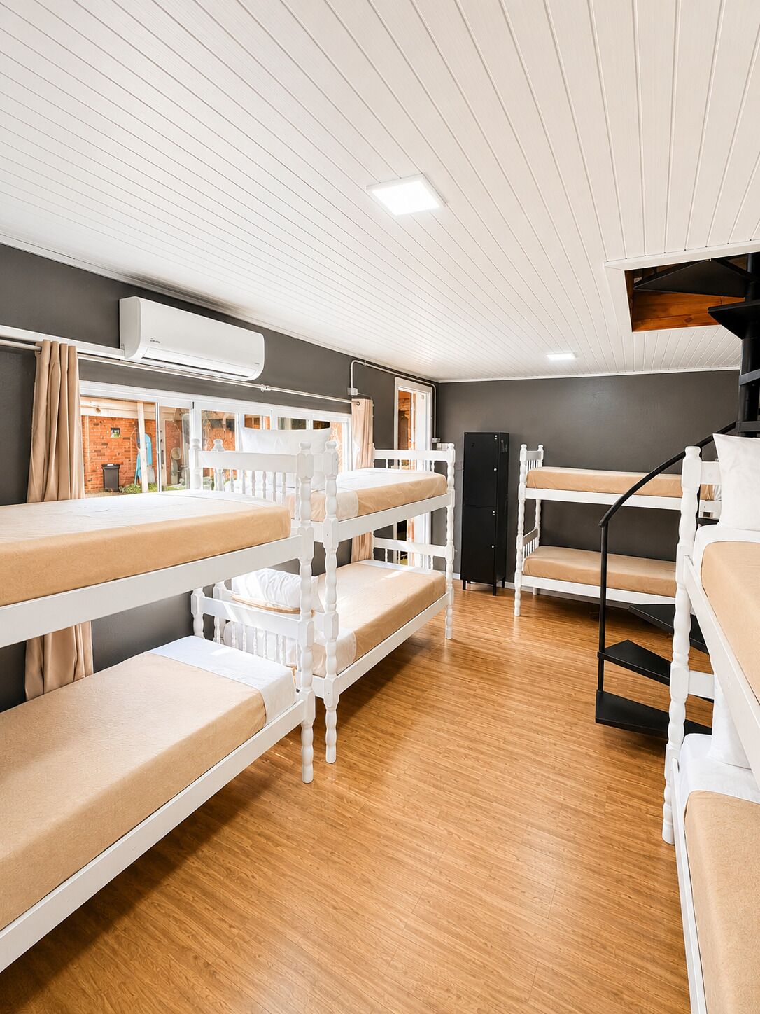 Quarto com beliche, ventilador de teto, ar condicionado e vista para o exterior.