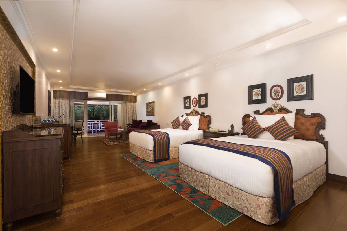 Quarto de hotel com duas camas, cómoda de madeira, televisão de ecrã plano e uma janela grande.