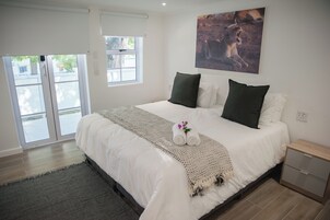 Quarto com uma cama grande, janela, quadro e mesa de cabeceira.