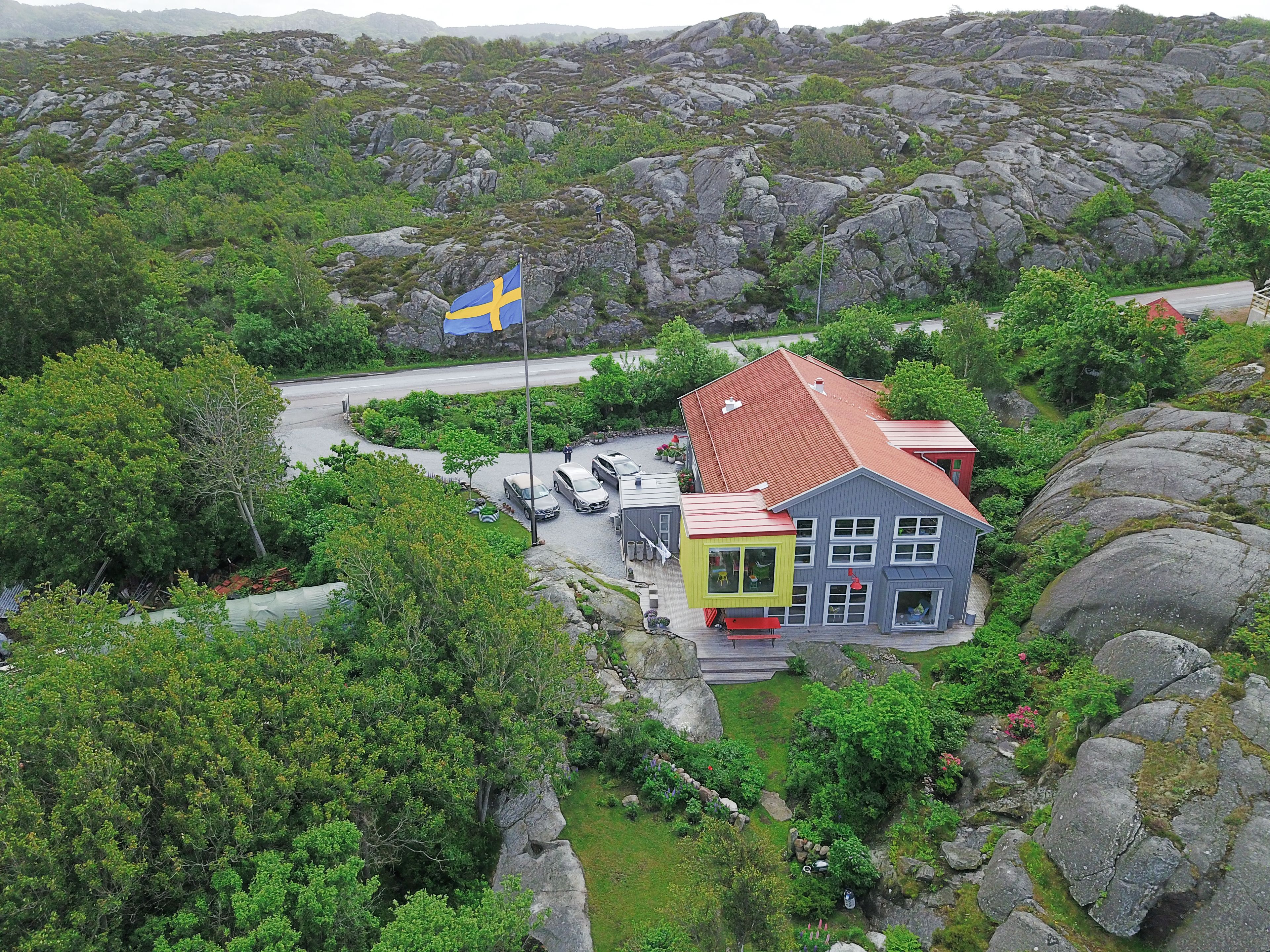 Uma casa com telhado vermelho, parte frontal amarela e uma bandeira azul.