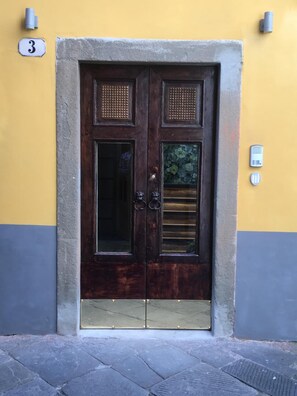Uma porta dupla de madeira com um painel de vidro, uma maçaneta de metal e uma pequena janela acima da porta.