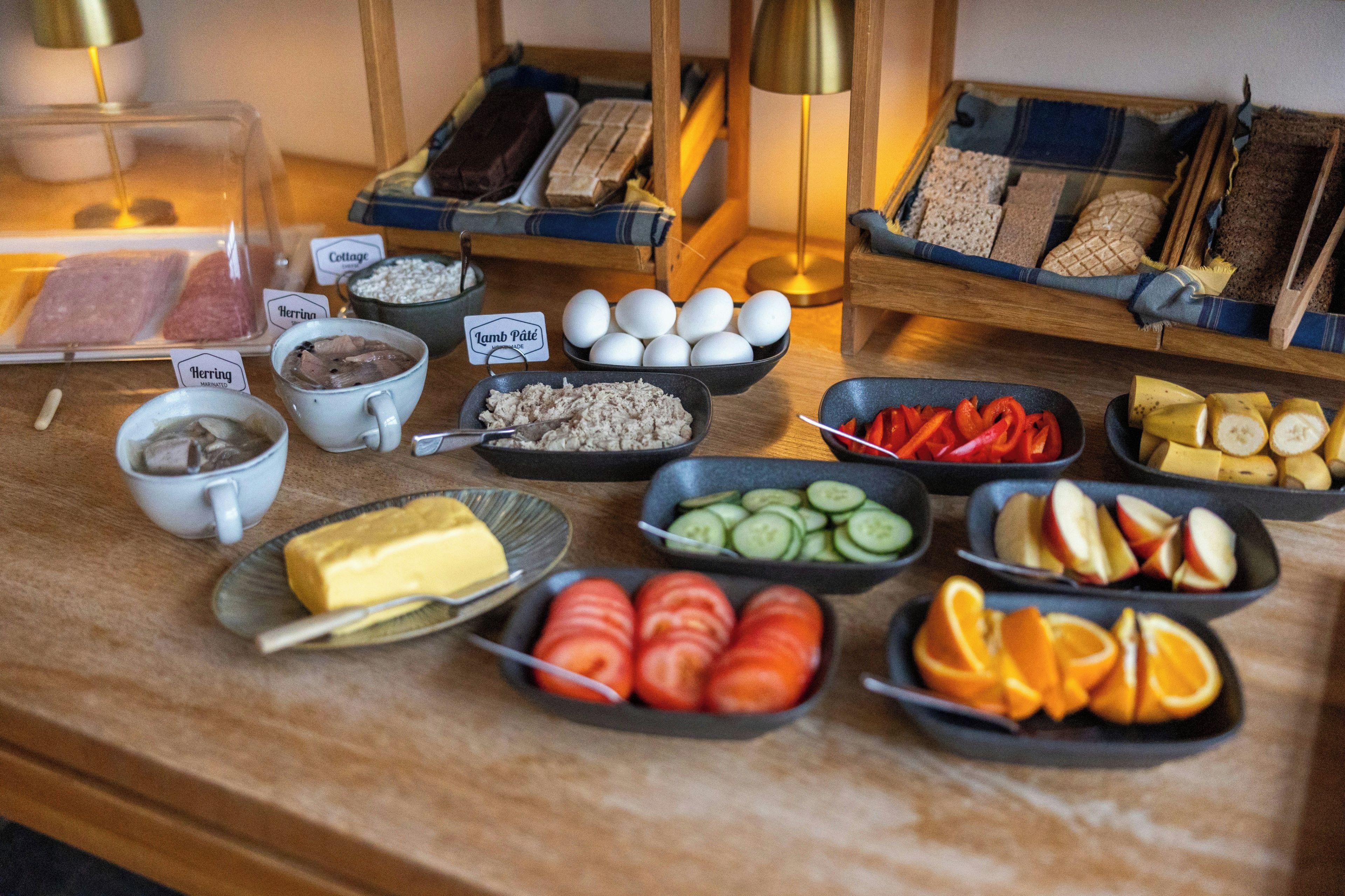 Buffet com diversas opções de comida, incluindo carnes, ovos, queijos e frutas.