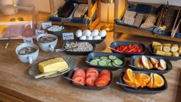 Buffet com diversas opções de comida, incluindo carnes, ovos, queijos e frutas.
