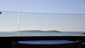 Vista de varanda com vista para um corpo de água e uma ilha ao longe.