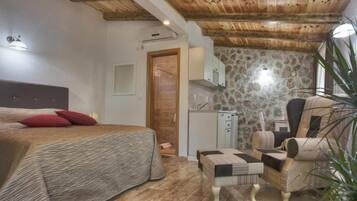 Um quarto com uma cama, uma cadeira, uma mesinha e um armário.