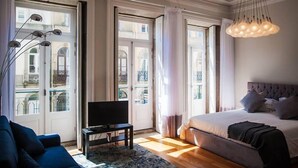 Quarto com cama grande, televisão e sofá.
