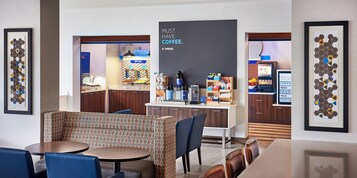 Um lobby moderno de hotel com espaço para café, área de estar e obras de arte emolduradas.