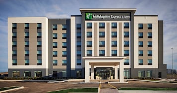Um hotel Holiday Inn Express & Suites com fachada moderna, vários andares e entrada central.