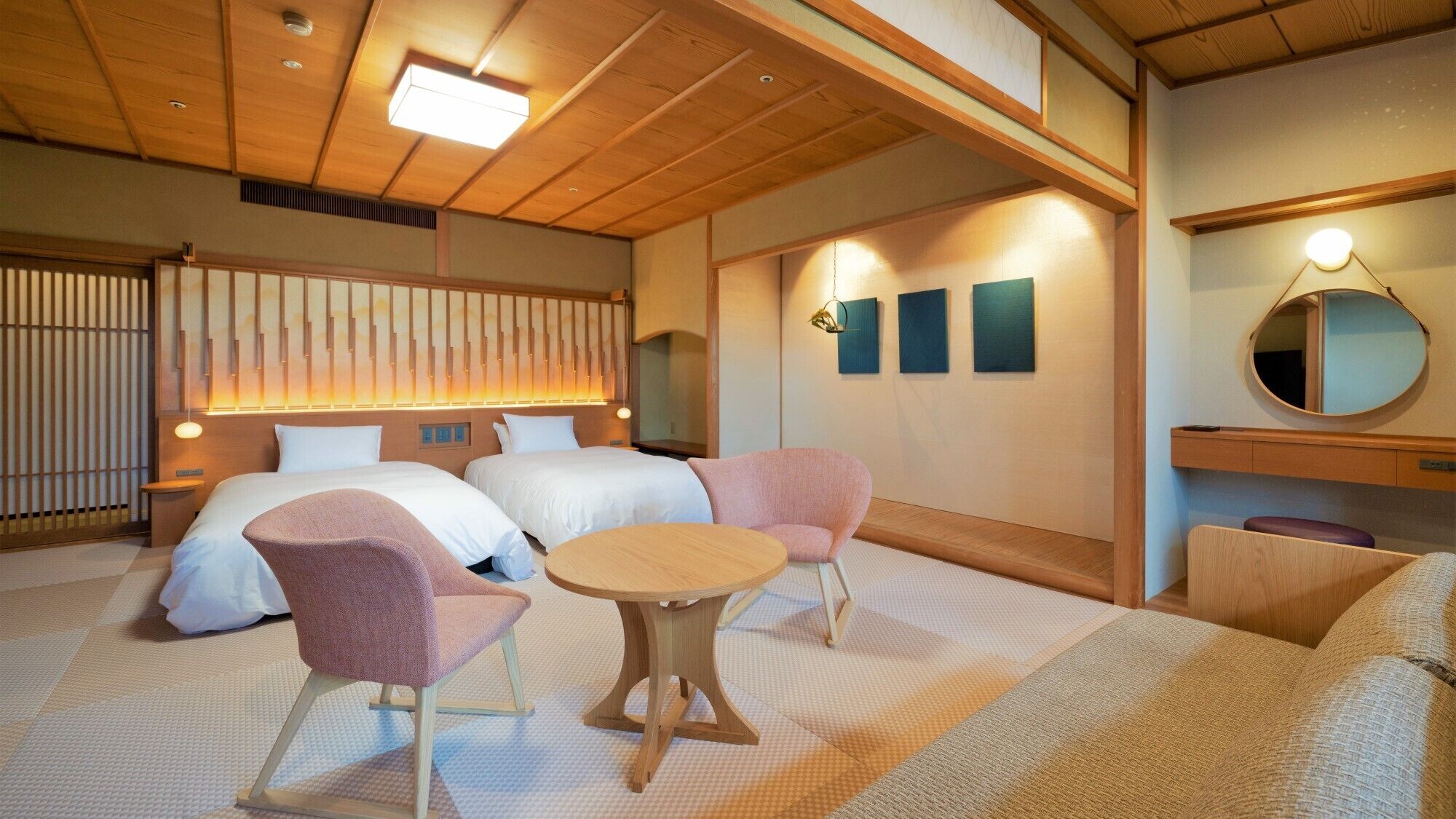 Quarto de hotel com duas camas, área de estar com uma mesa e um espelho.