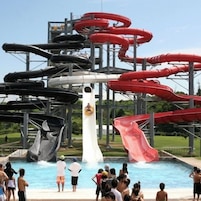 Um parque aquático com várias escorregas e uma área de piscinas.