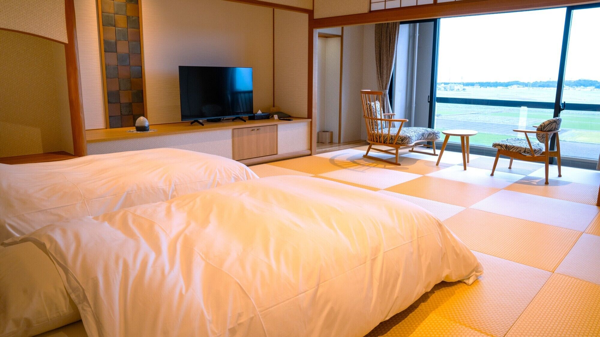 Quarto de hotel com duas camas, televisão, escrivaninha e vista para a água.