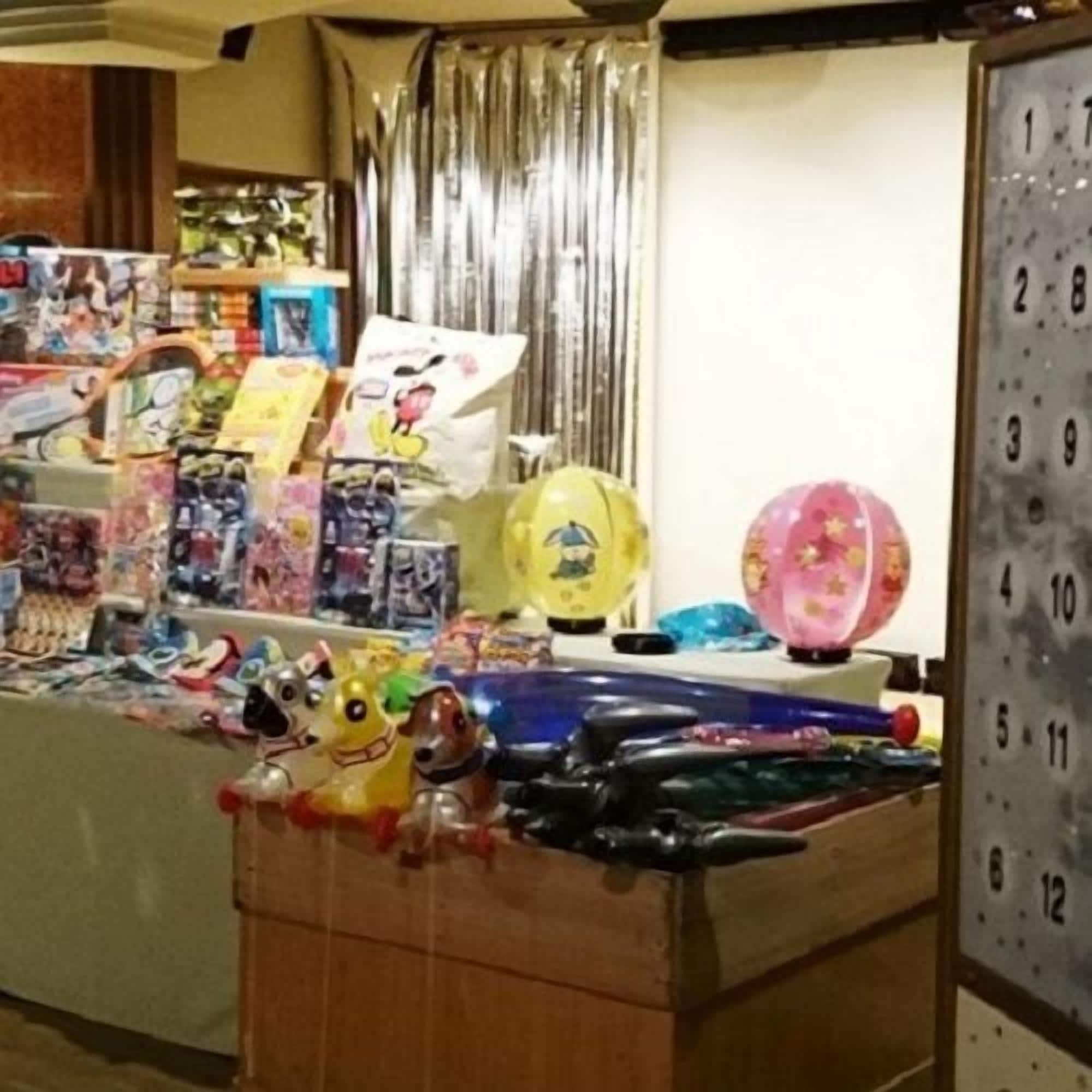 Exposição de brinquedos e jogos, incluindo um carrinho e um globo terrestre, em um quarto com um calendário na parede.