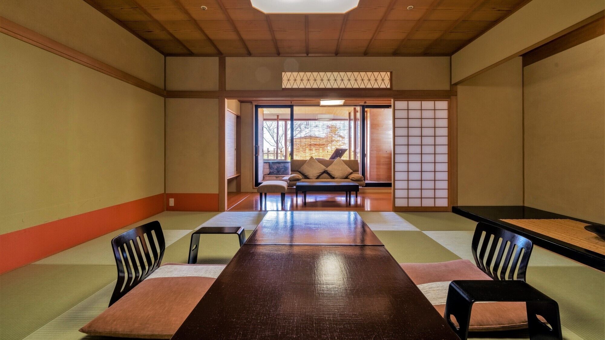 Um quarto japonês tradicional com tatames, uma mesa baixa e um sofá.