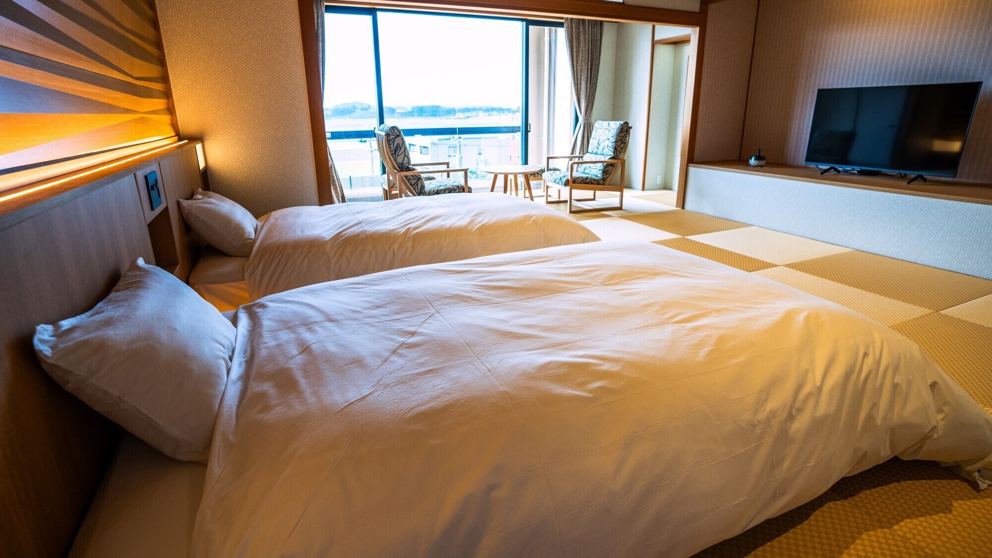 Quarto de hotel com duas camas, televisão e vista para o mar.