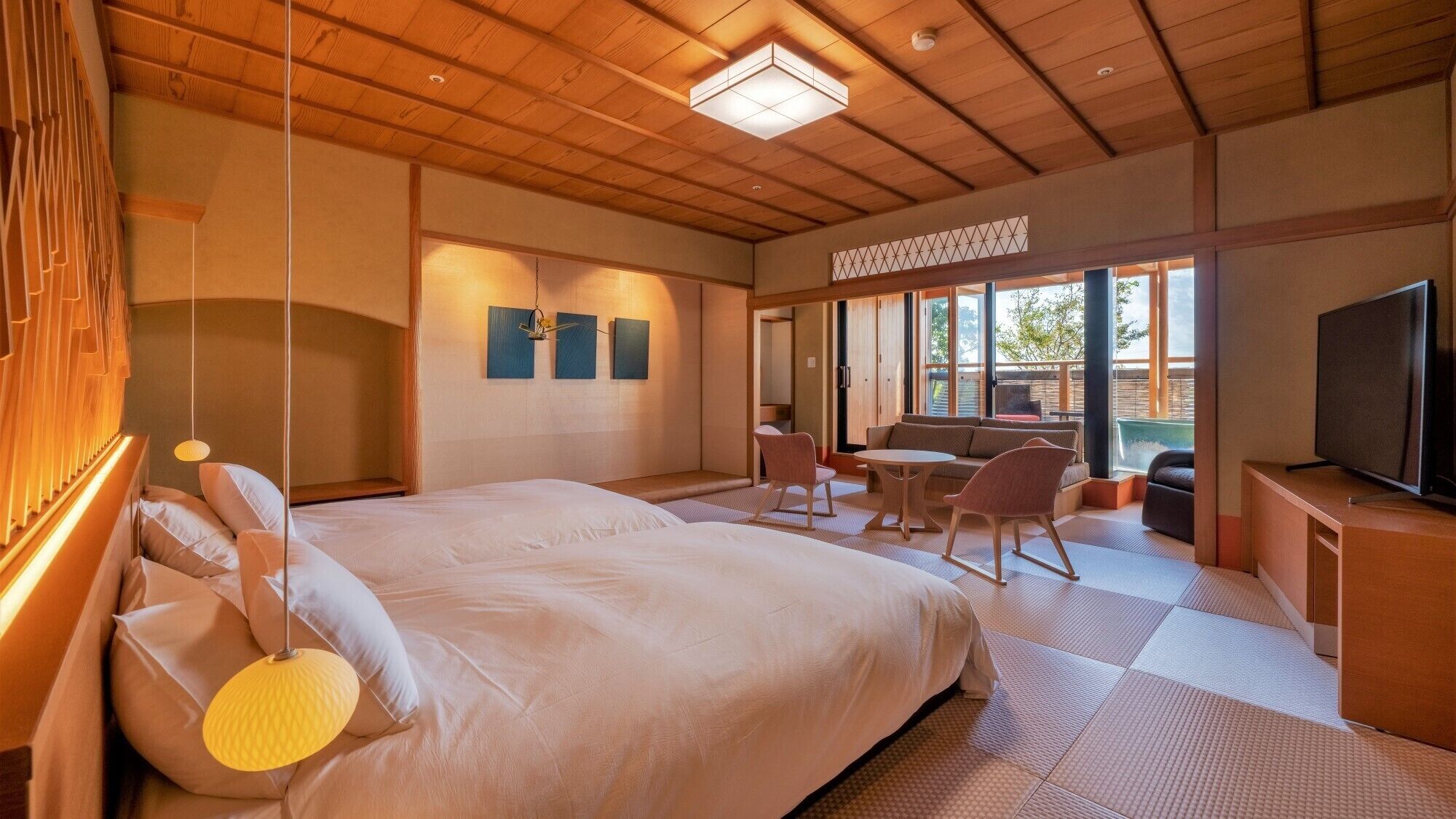 Quarto de hotel com uma cama grande, televisão, área de refeições e vista para o exterior.