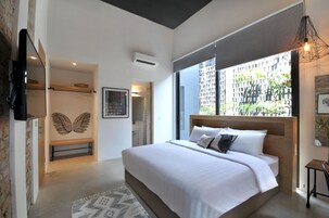 Quarto moderno com uma cama grande, um banco, televisão fixada na parede e vista para o horizonte urbano por uma janela ampla.