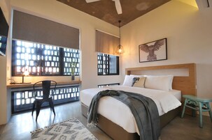 Quarto com uma cama, escrivaninha, cadeira e janela com persianas.