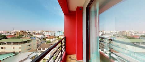 Varanda com parede vermelha e vista para o horizonte urbano.