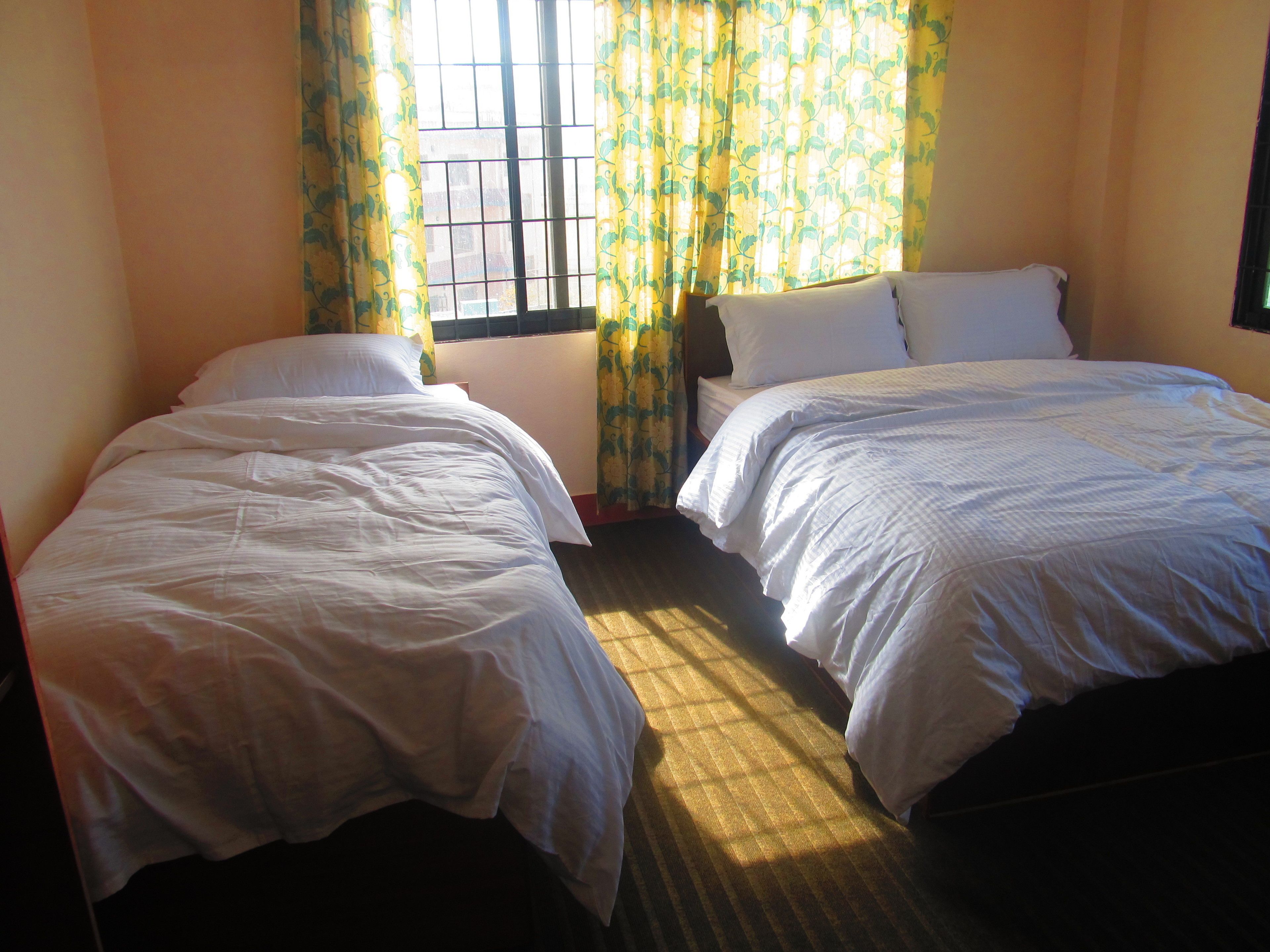 Quarto com duas camas de solteiro, janela com vista e radiador.