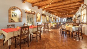 Restaurante com vigas de madeira e soalho em azulejos, com várias mesas e cadeiras.