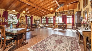 Um quarto amplo com vigas de madeira, uma grande mesa de jantar e um tapete estampado.