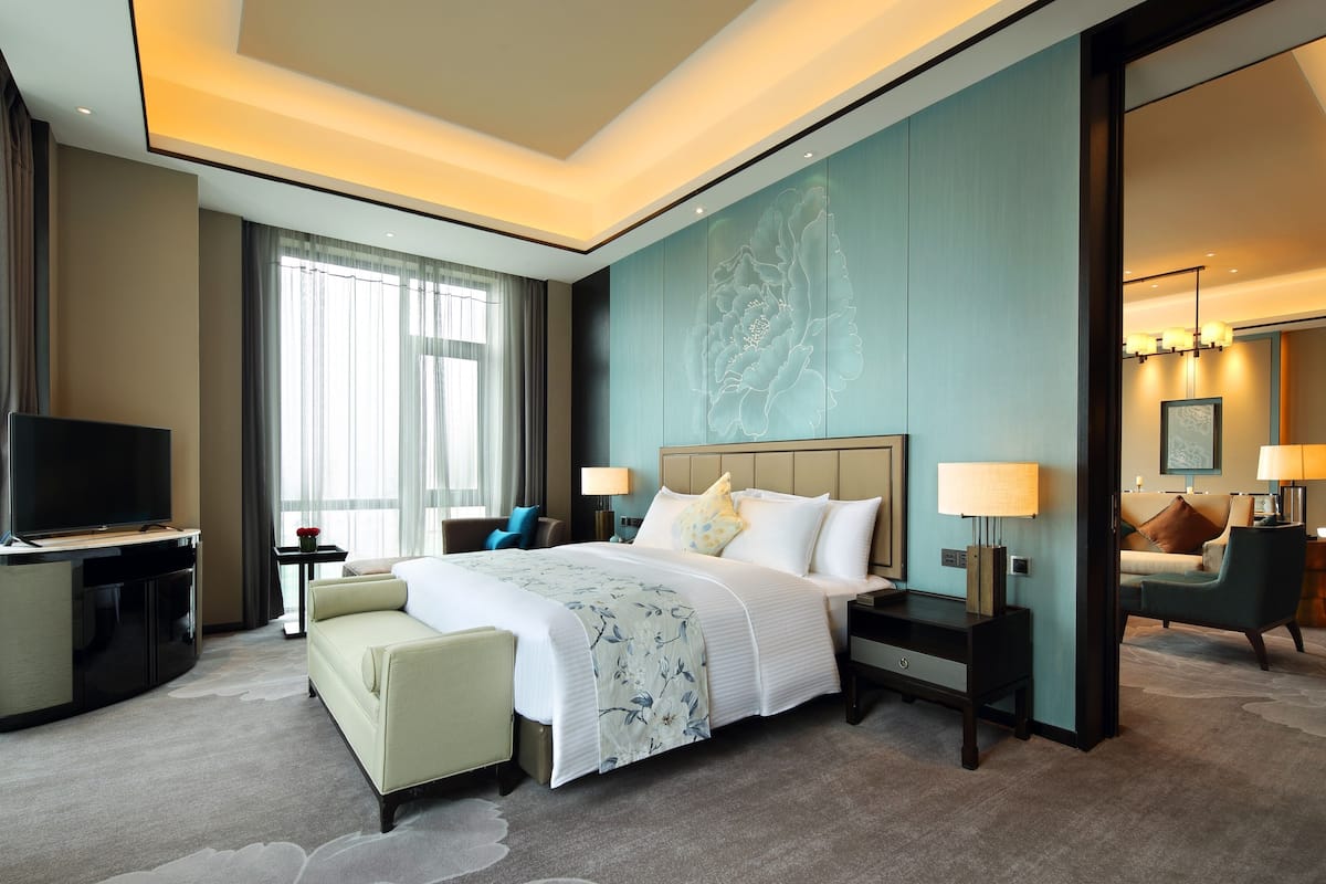Quarto de hotel com uma cama grande, televisão, escrivaninha e uma cadeira.