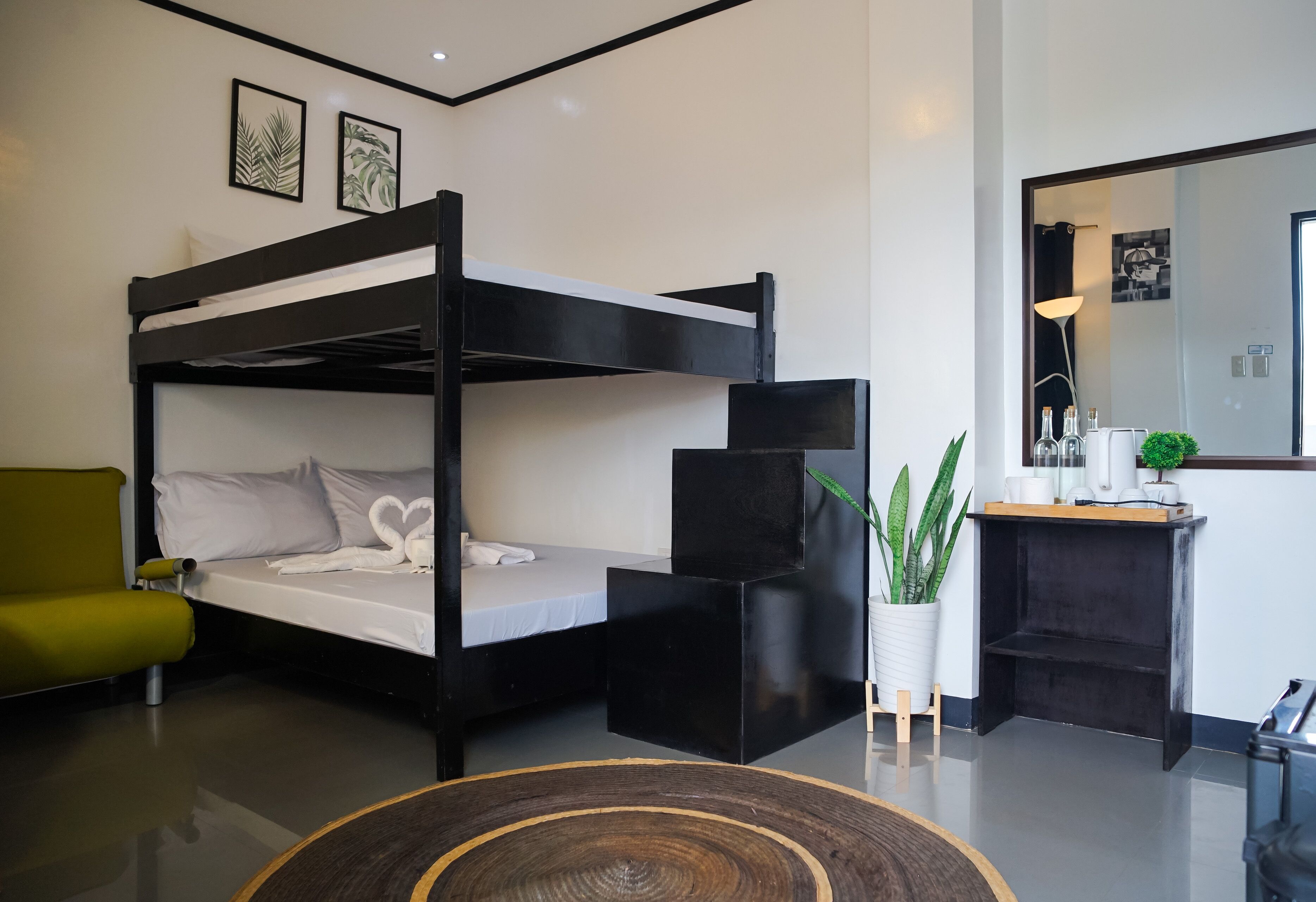 Um quarto moderno com uma cama beliche, uma cadeira verde, uma escrivaninha com um espelho e um vaso de planta.