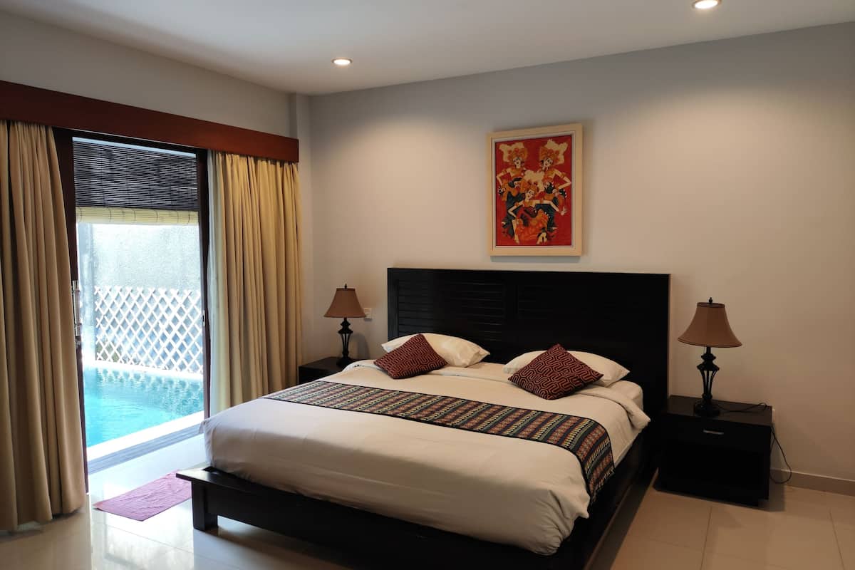 Quarto com cama, duas mesas de cabeceira, um criado-mudo, uma janela com cortinas e um quadro na parede.