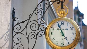 Um relógio de estilo antigo com moldura dourada e design preto ornamentado, fixado na parede.