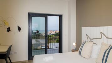 Quarto de hotel com cama, escrivaninha e varanda com vista para edifícios.