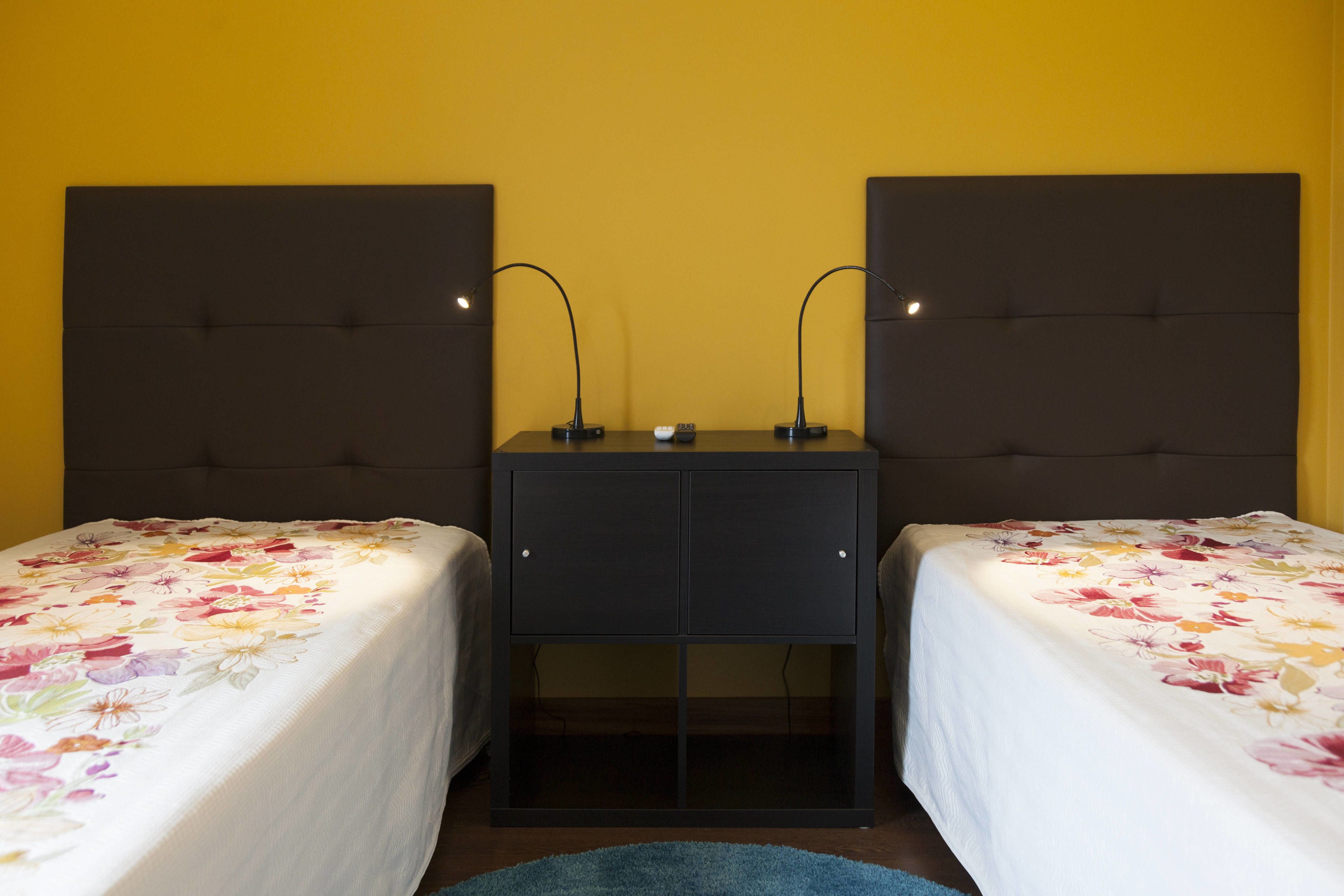 Quarto com duas camas, uma mesinha de cabeceira e um pequeno armário.