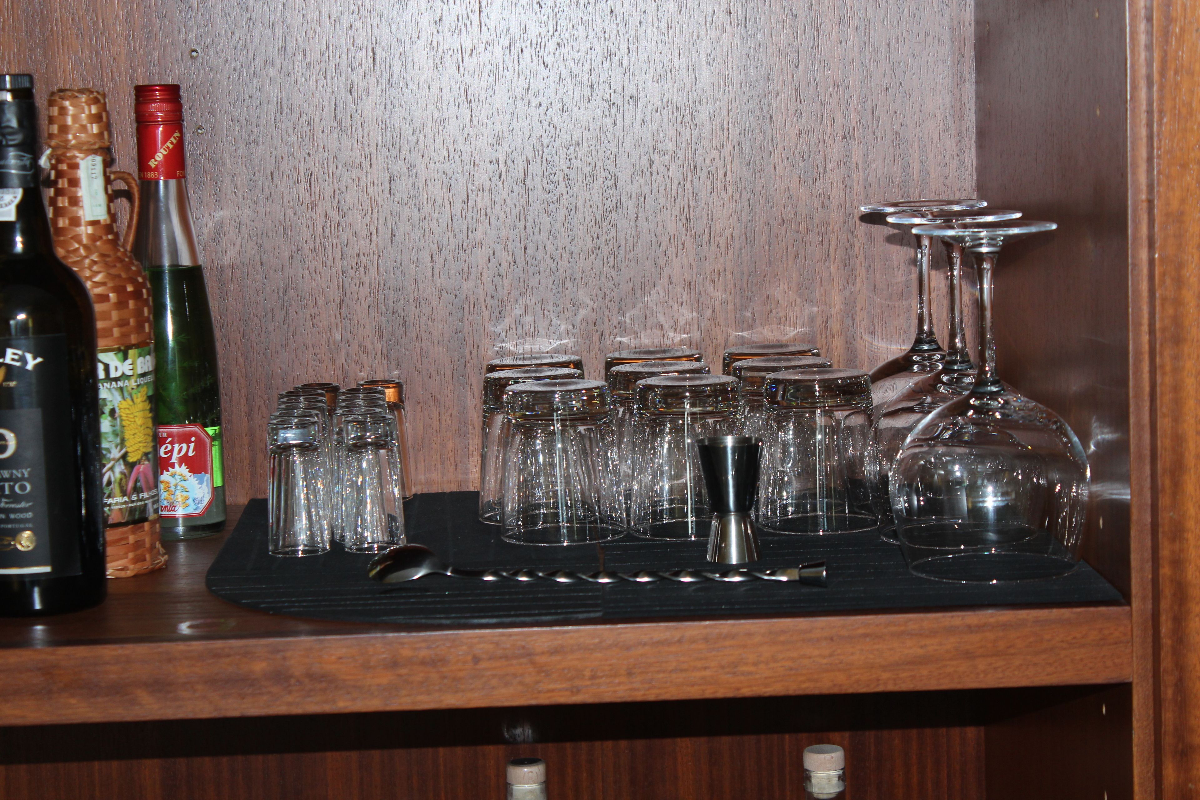 Disposição de bar com garrafas, copos e abridor.