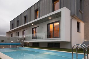 Um edifício moderno com piscina, janelas amplas e varanda.