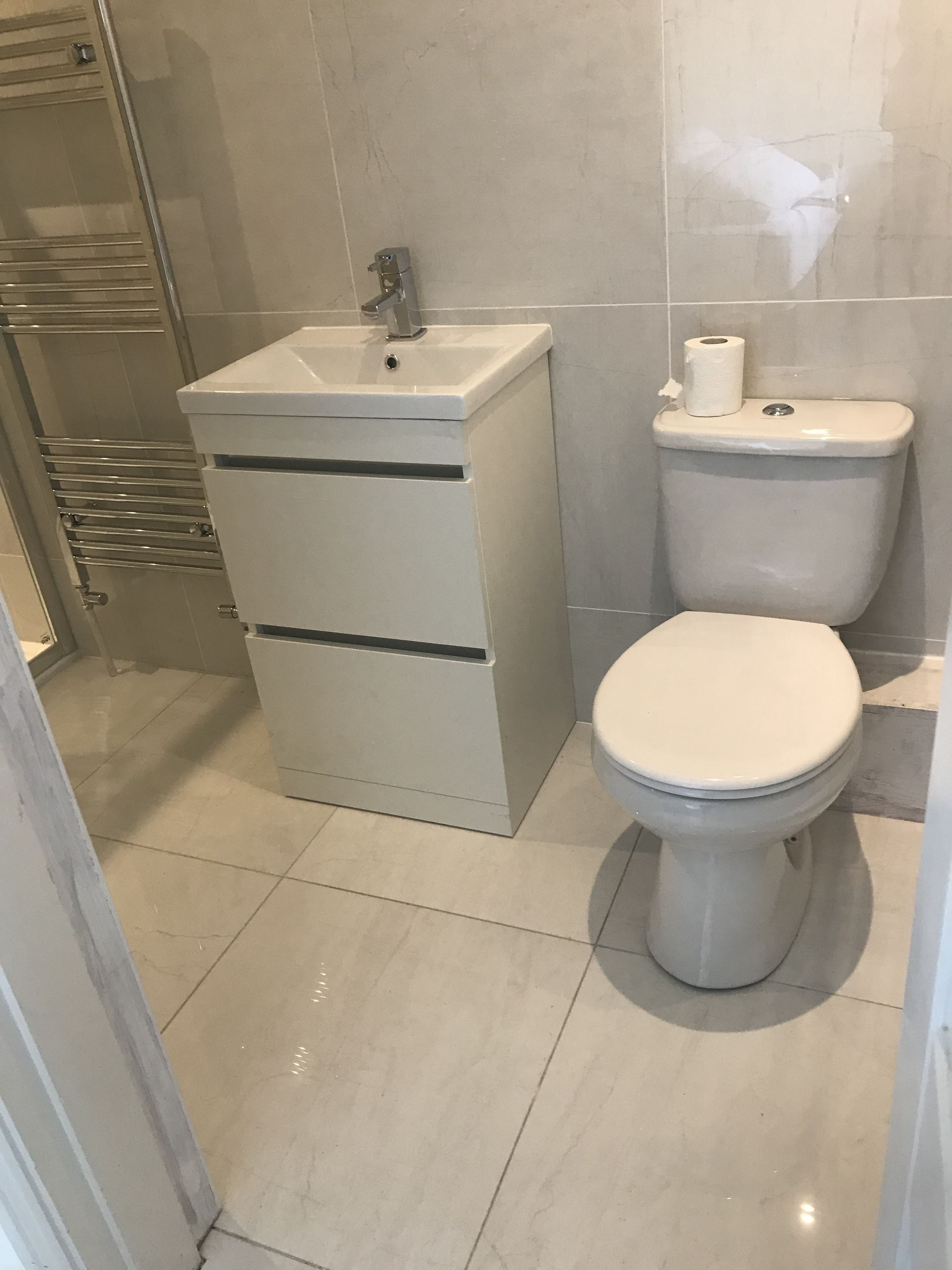 Um banheiro com vaso sanitário, pia e porta-toalhas.