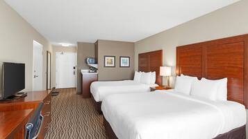 Quarto de hotel com duas camas, uma mesa de trabalho, televisão, minibar e porta de banheiro.