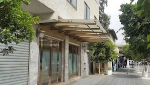 Uma rua estreita com um edifício que apresenta uma entrada coberta e um toldo fechado.