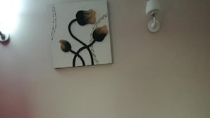 Quarto com cabeceira de couro preto, colcha branca e mesa de cabeceira com luminária.