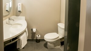 Um banheiro moderno com pia branca, vaso sanitário e box de vidro.