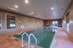Piscina interior com água cristalina, placa indicando 'proibido mergulhar' e boia salva-vidas.