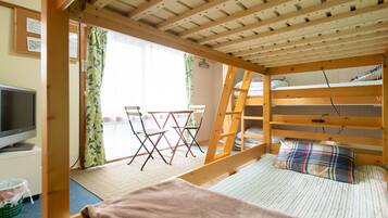 Quarto com beliche, teto de madeira, televisão, escrivaninha e janela com cortinas.