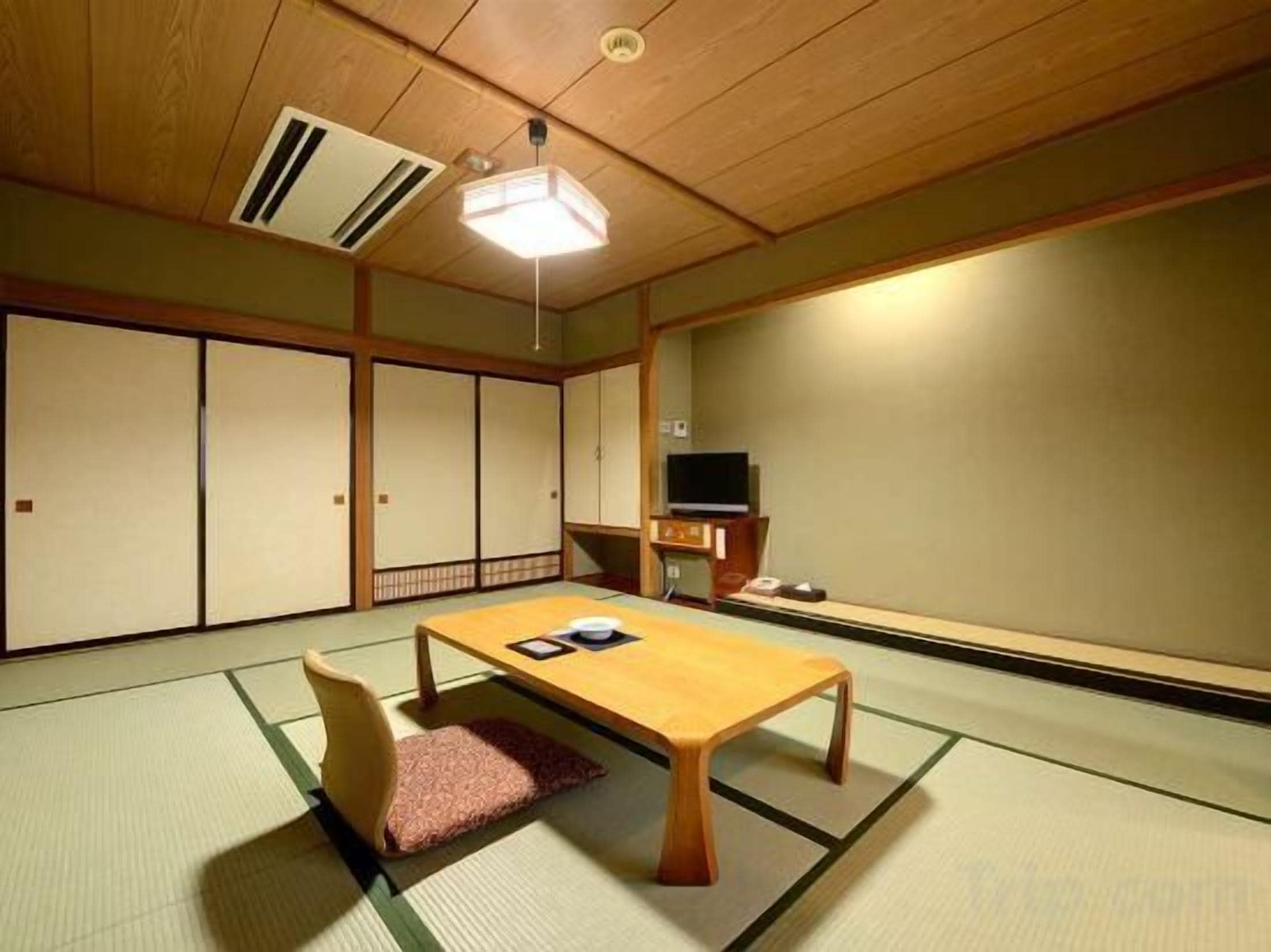 Um quarto japonês tradicional com tatames, uma mesa de madeira baixa e portas deslizantes.