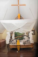 Uma cama com dossel, cabeceira de madeira e almofada decorativa.