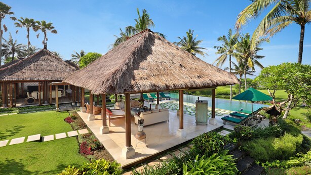 Um resort com construções de palha, área de piscina e vegetação exuberante.